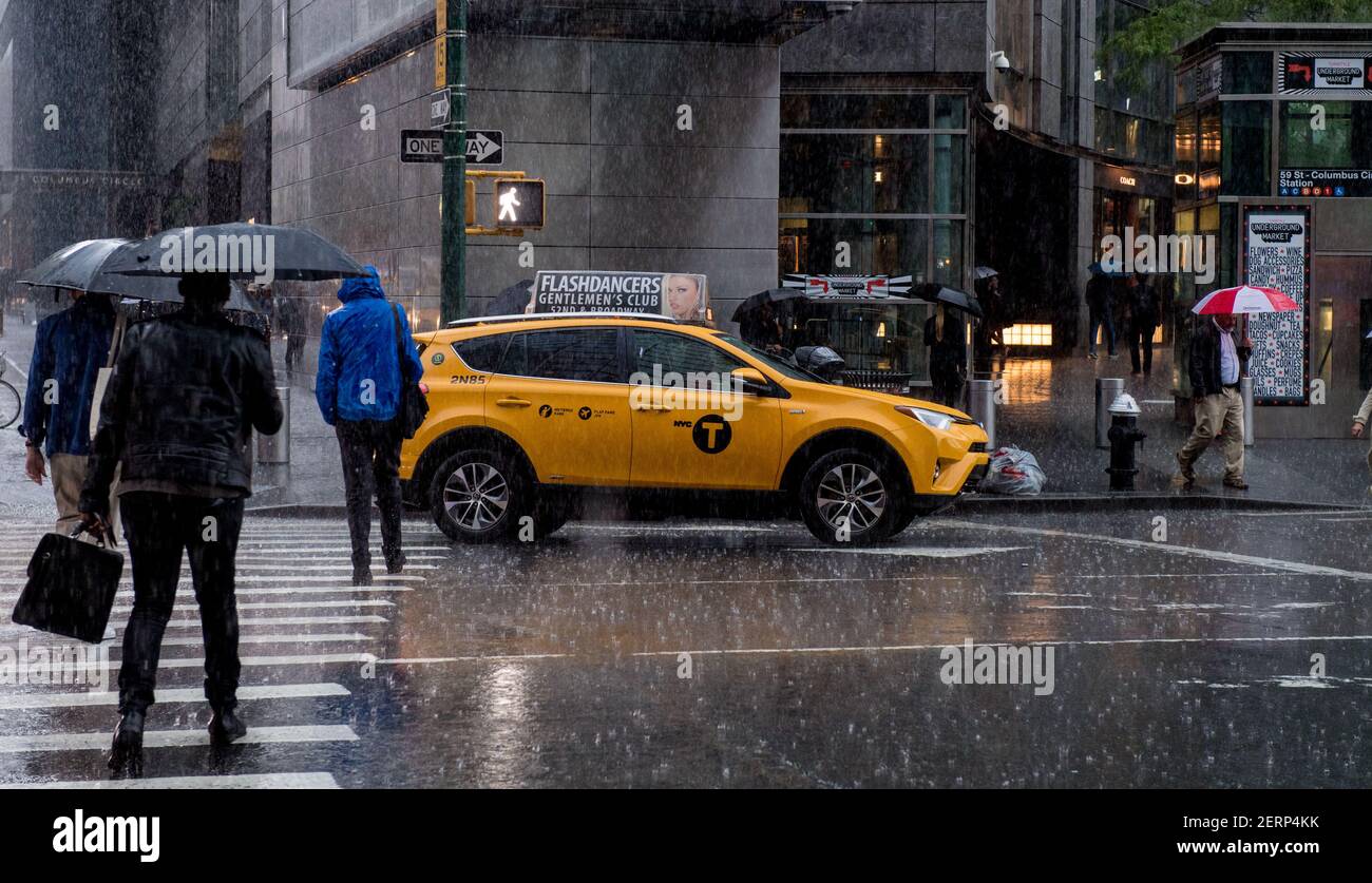 People shelter from the heavy rain beneath umbrellas and ponchos in New ...