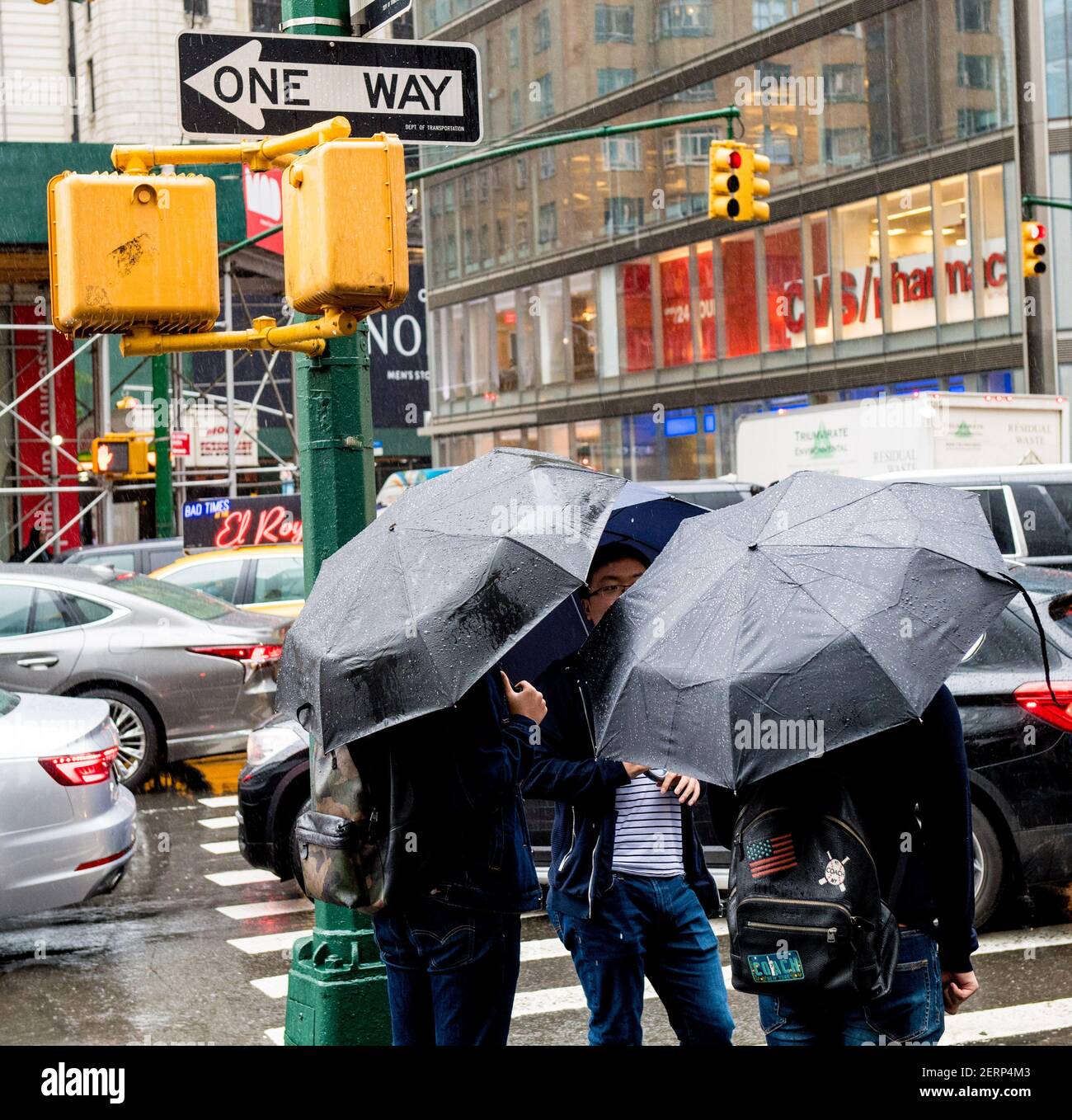 People shelter from the heavy rain beneath umbrellas and ponchos in New ...