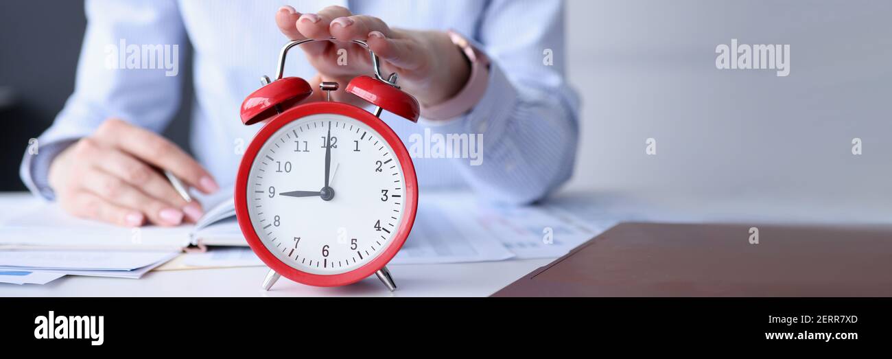 Female hand turning off red alarm clock at workplace closeup Stock ...