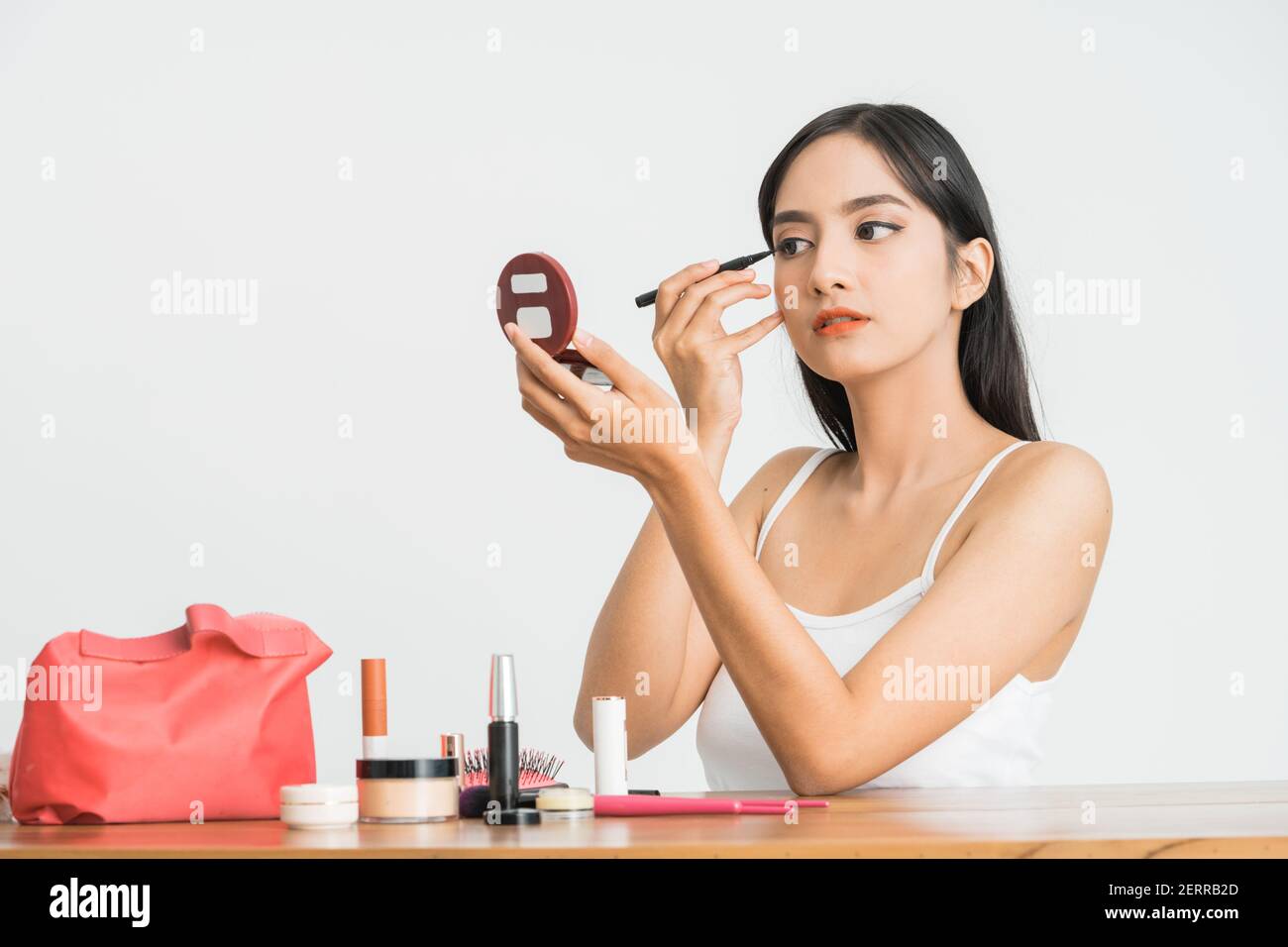 Mixed Race Asian Woman Putting Eye Liner On Eyelid On White Background