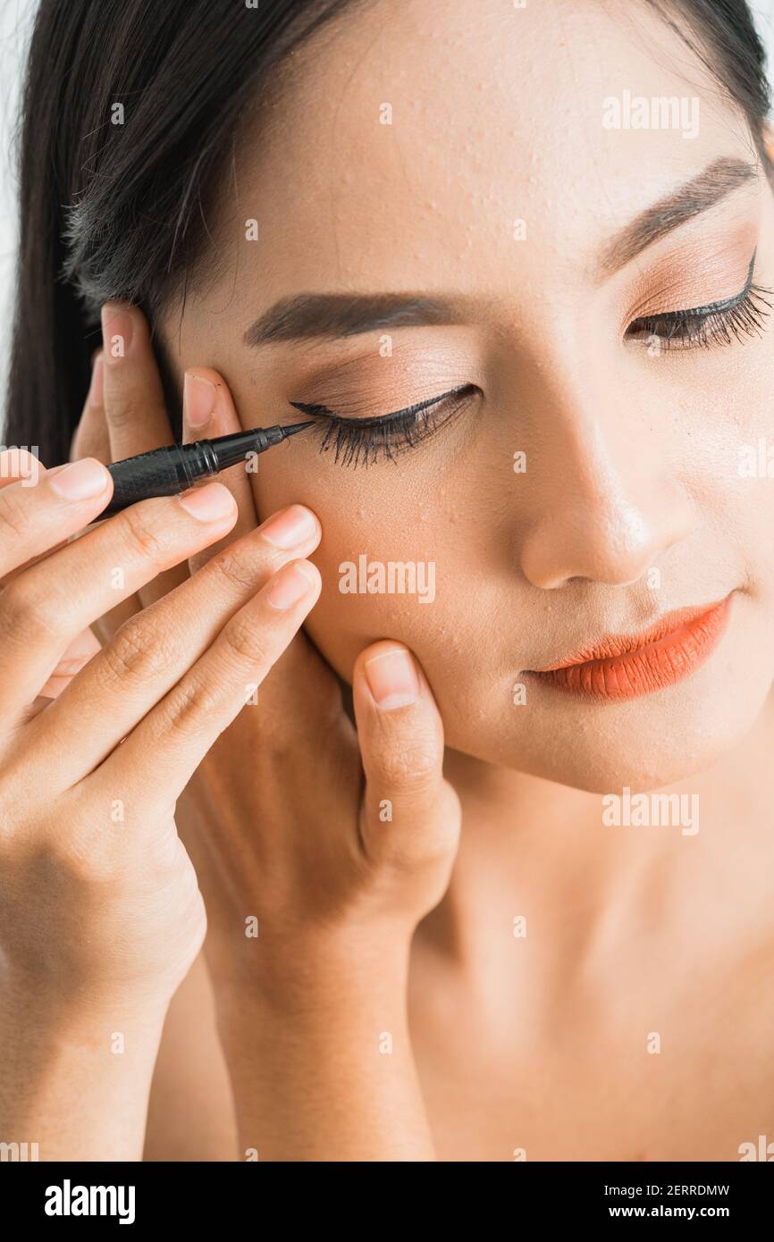 Mixed Race Asian Woman Putting Eye Liner On Eyelid On White Background