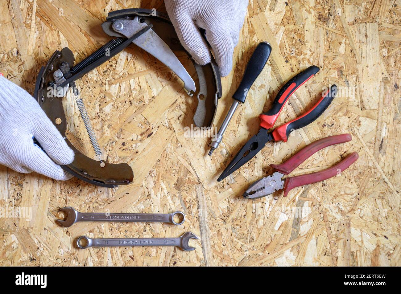 car drum brake disassembled in men's gloved hands and a set of various ...