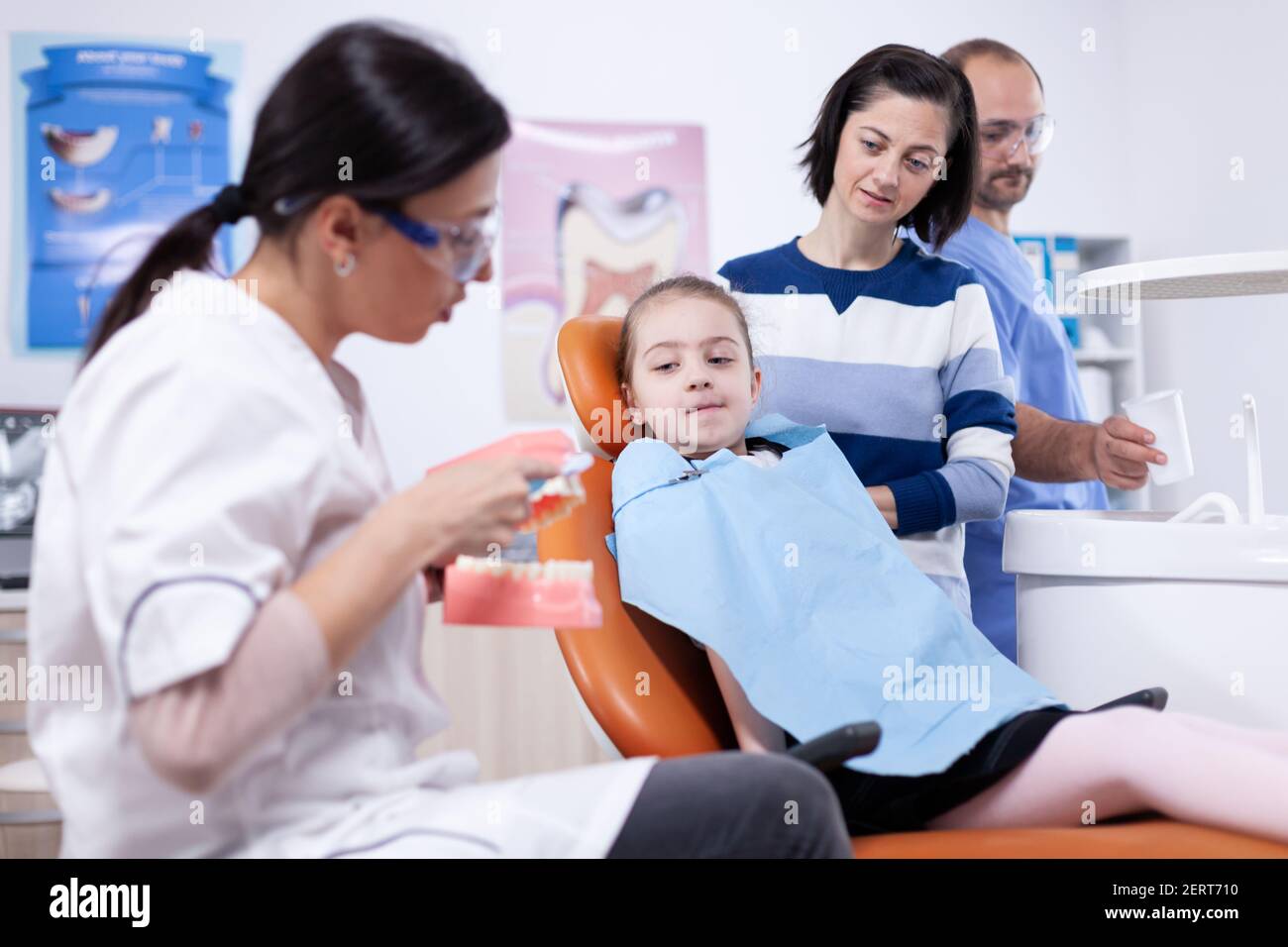 Child learning how to use tootbursh from young dentist in Little girl ...