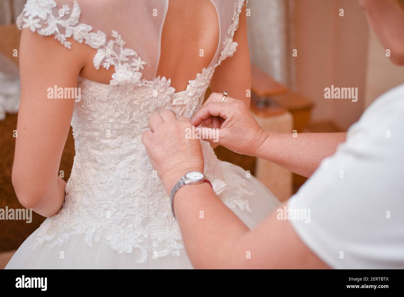 The bride's mother helps the bride get dressed Stock Photo - Alamy