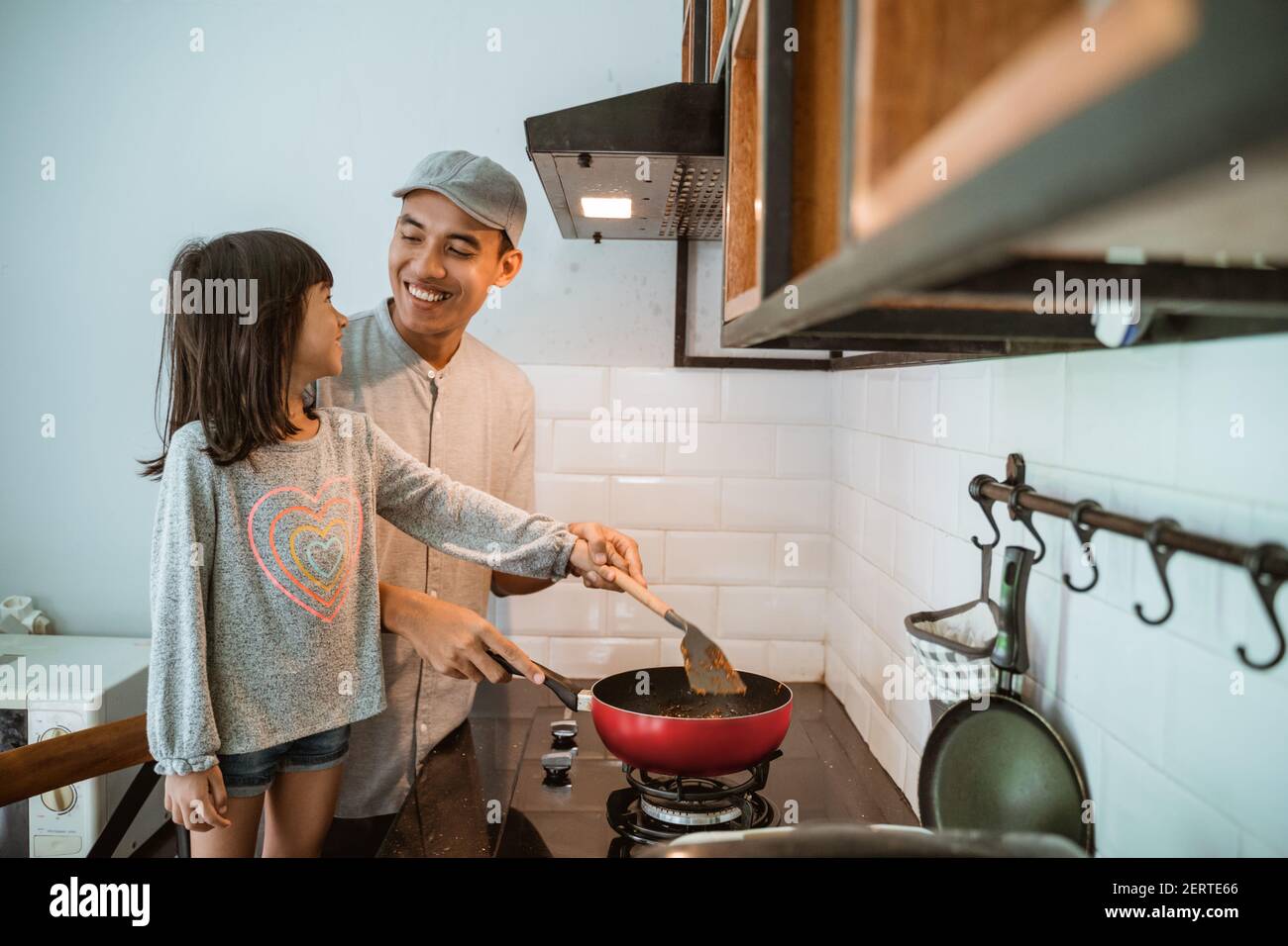 portrait of happy asian father and daughter cooking together in modern ...