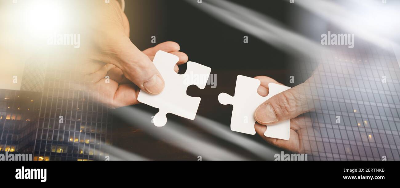 Hands joining two puzzle pieces, teamwork concept; multiple exposure ...