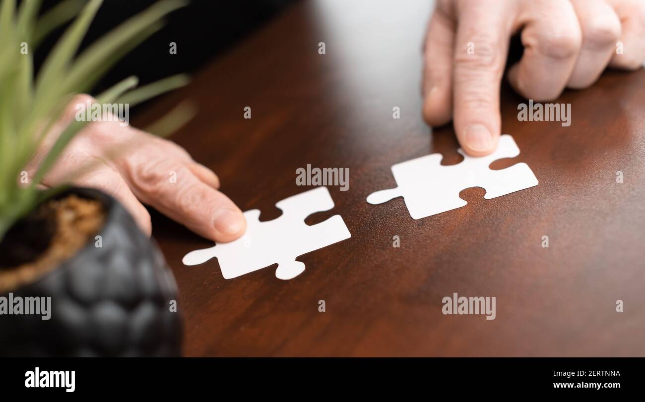 Hands joining two puzzle pieces, teamwork concept Stock Photo - Alamy