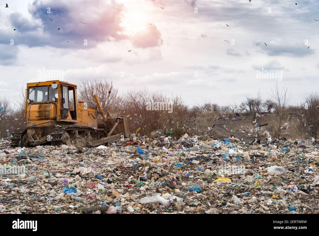 A bulldozer tractor pushes garbage in a city dump on the background ...