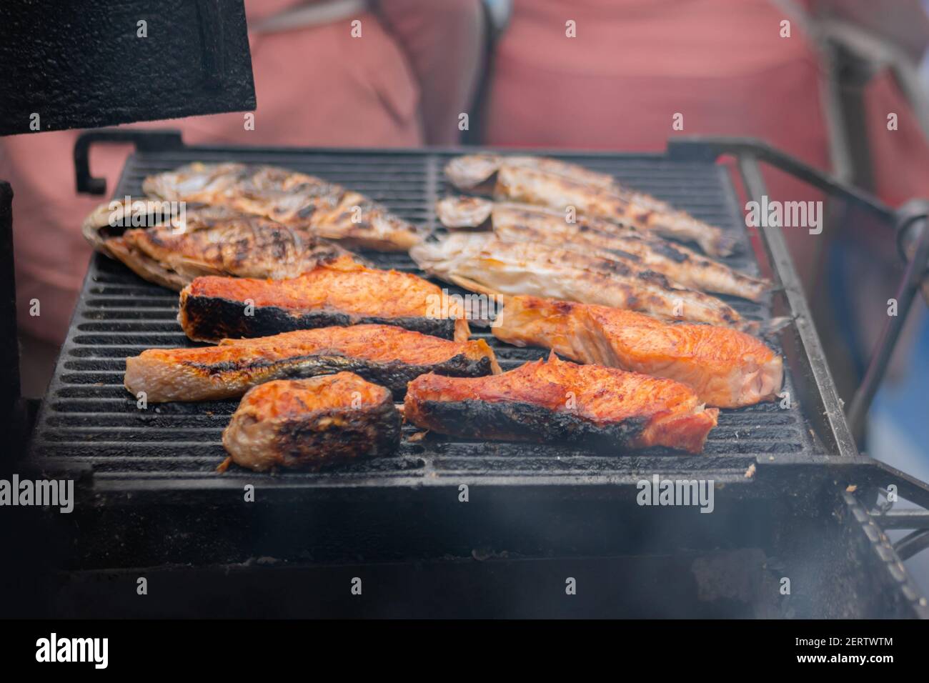 Cooking salmon, tiger shrimp, prawn skewers and mackerel fish on grill ...