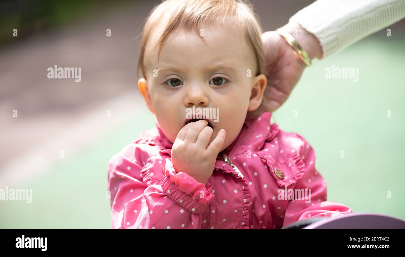 Portrait of cute baby girl eating a biscuit in playground Stock Photo ...