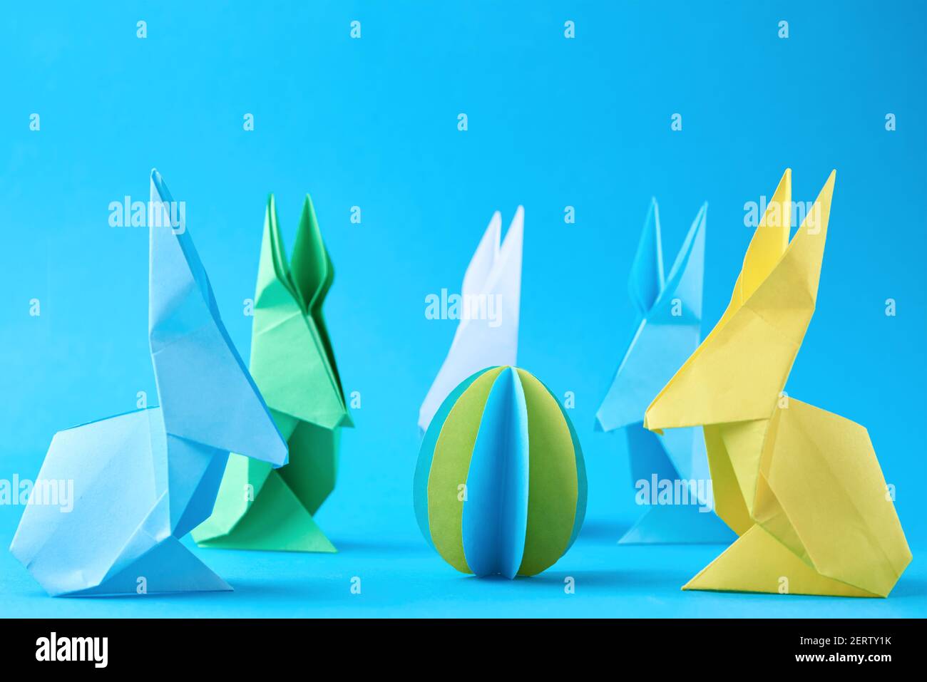 Paper origami Esater rabbits and colored eggs on blue background ...