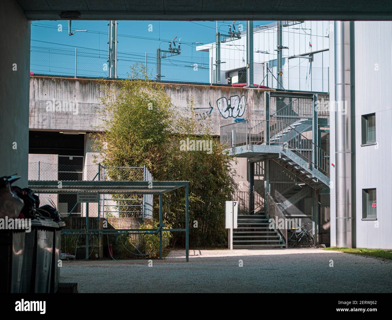 Street photography of a brightly lit alley way and Train line overhead ...