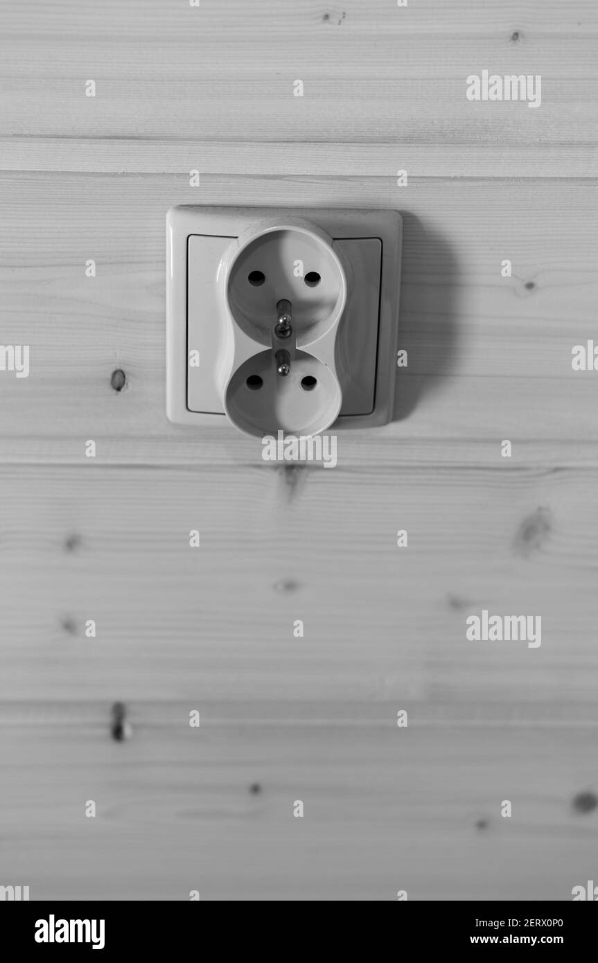 Electric white plastic sockets on a wooden wal Stock Photo - Alamy