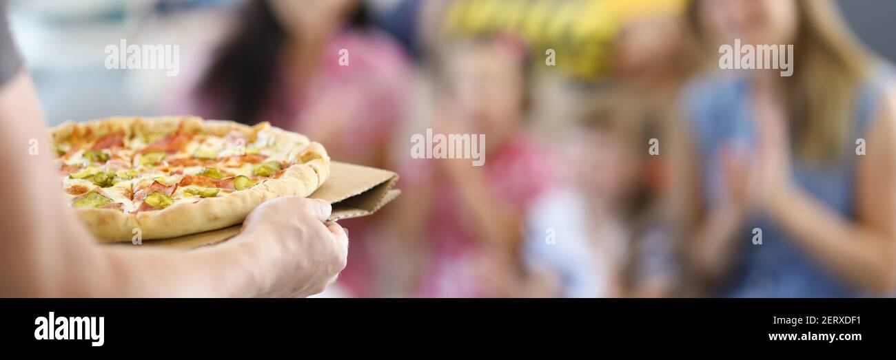 Male hands hold pizza on background of people Stock Photo - Alamy