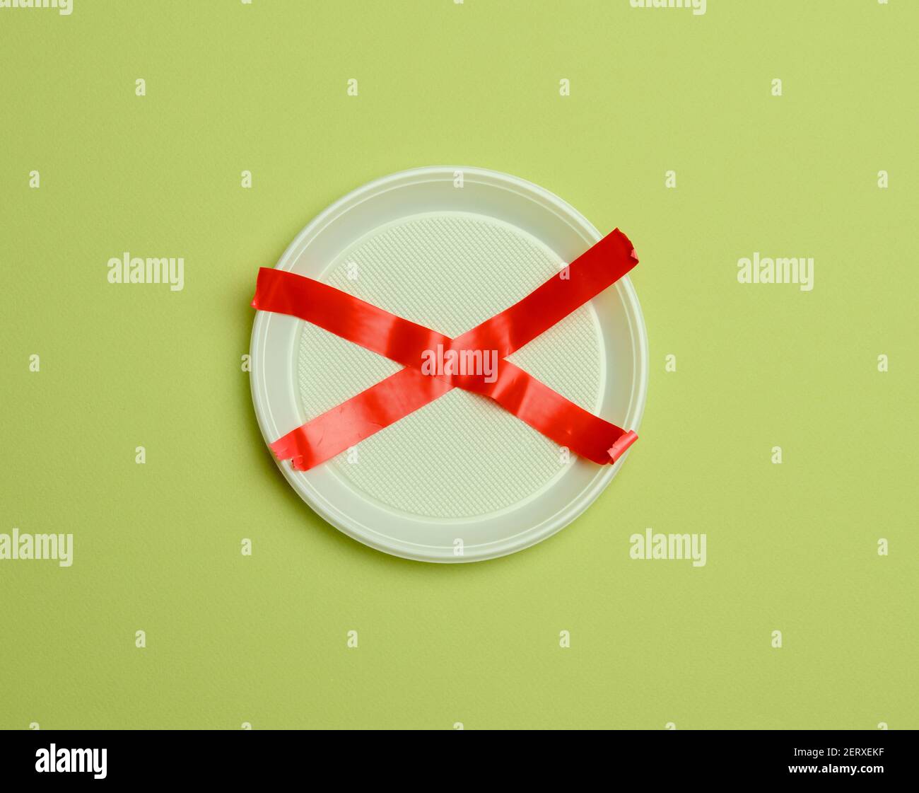 empty white plastic plate sealed with red tape, green background. Diet ...