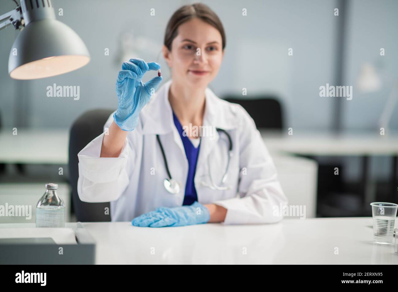 A Young Female Doctor In Blue Medical Gloves Shows A Patient A Capsule