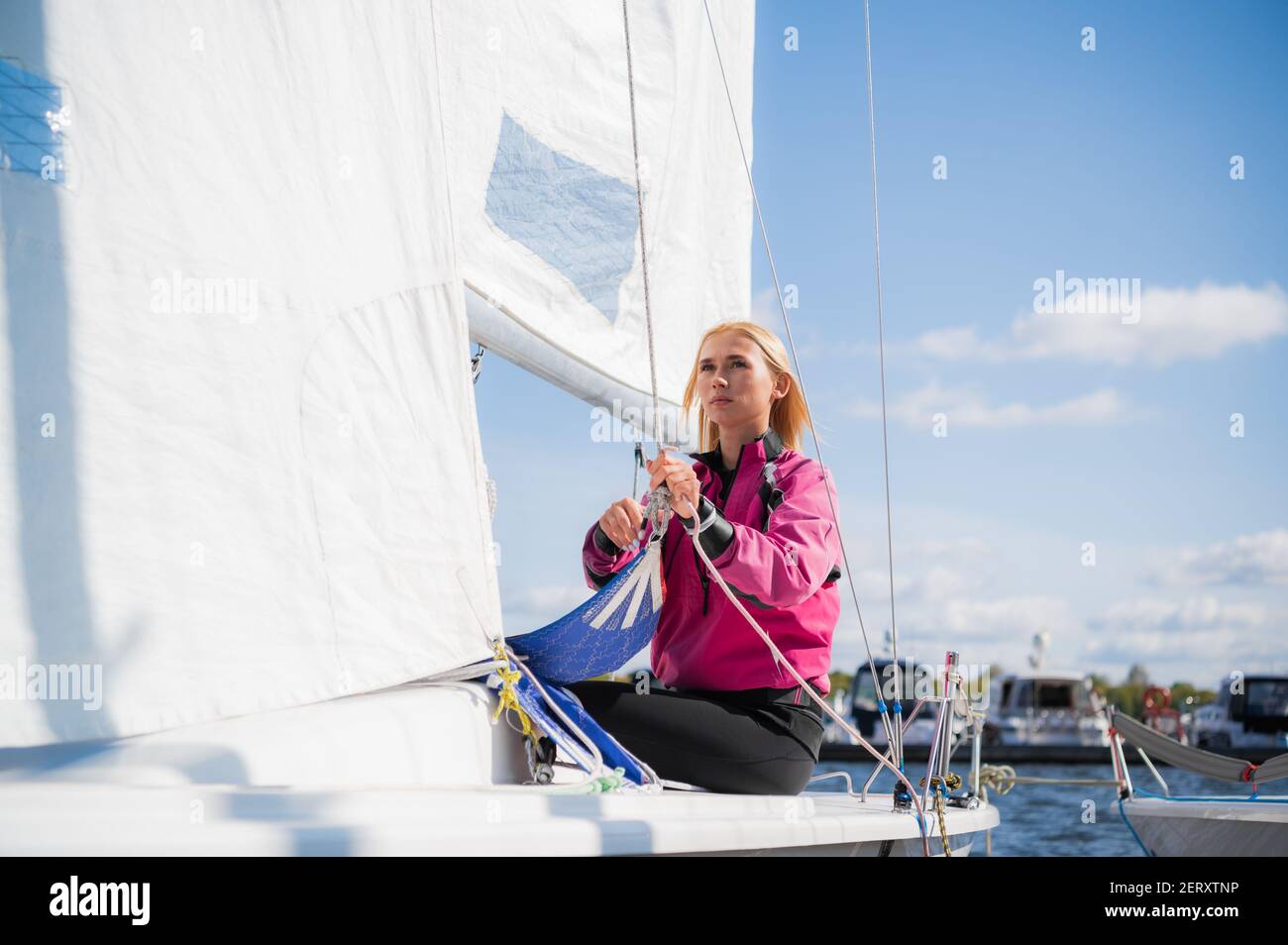 At the yacht parking lot, a young yachtsman in a pink windbreaker ...