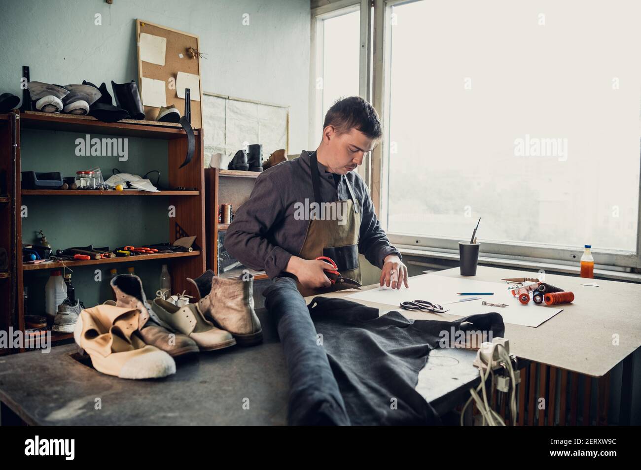 An experienced shoemaker in a shoe production workshop makes a pattern ...