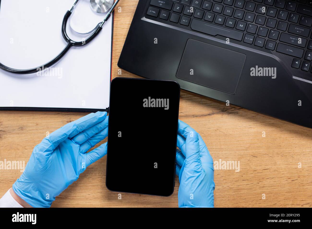 Hands of a paramedic in latex gloves holding a tablet. On the table a ...