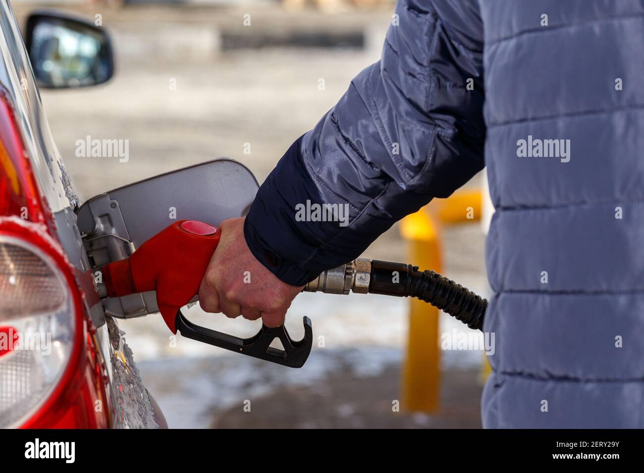old man hand in blue warm jacket refueling gray metallic car on gas ...