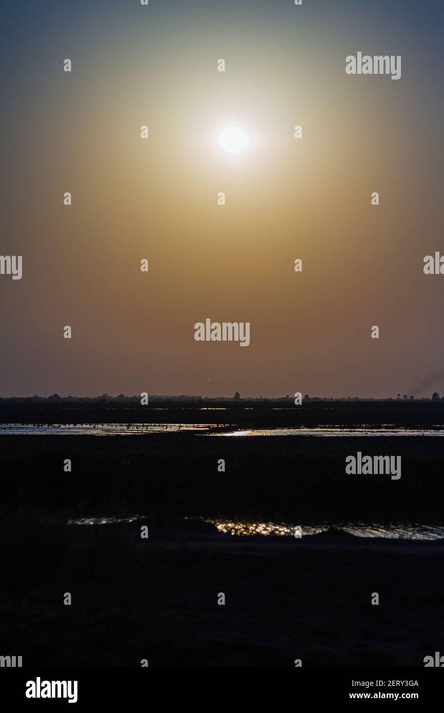 A beautiful landscape view of the brightly shining sunset sun over a ...