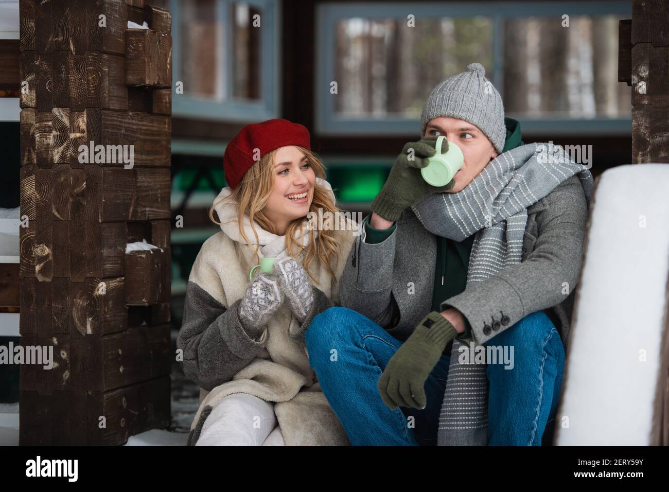 Beautiful blonde and cute man bask in the gazebo, drink hot drinks ...