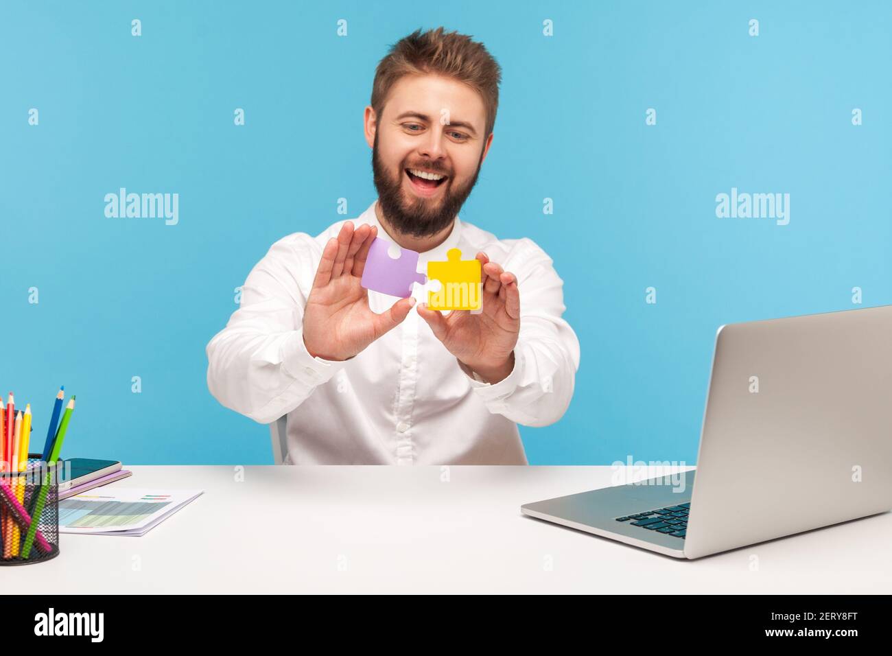 Happy smiling man office worker putting together two colored pieces of ...