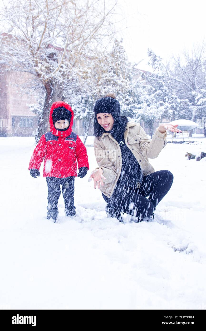 mother and the little boy are playing in winter park, mother and cute ...