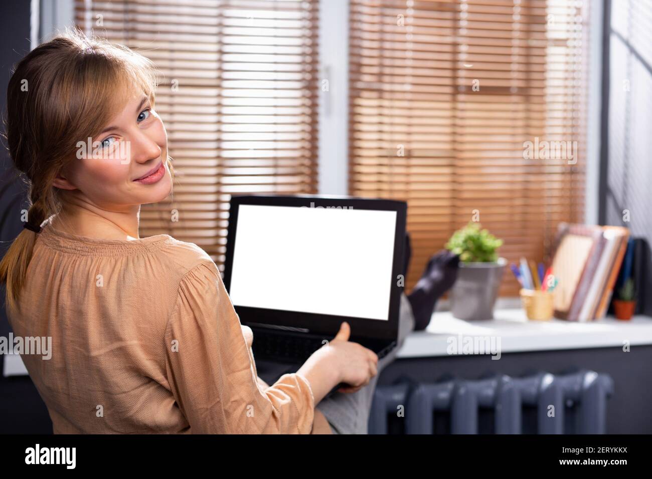 Woman relaxing on a chair, putting her foot on the window at home ...