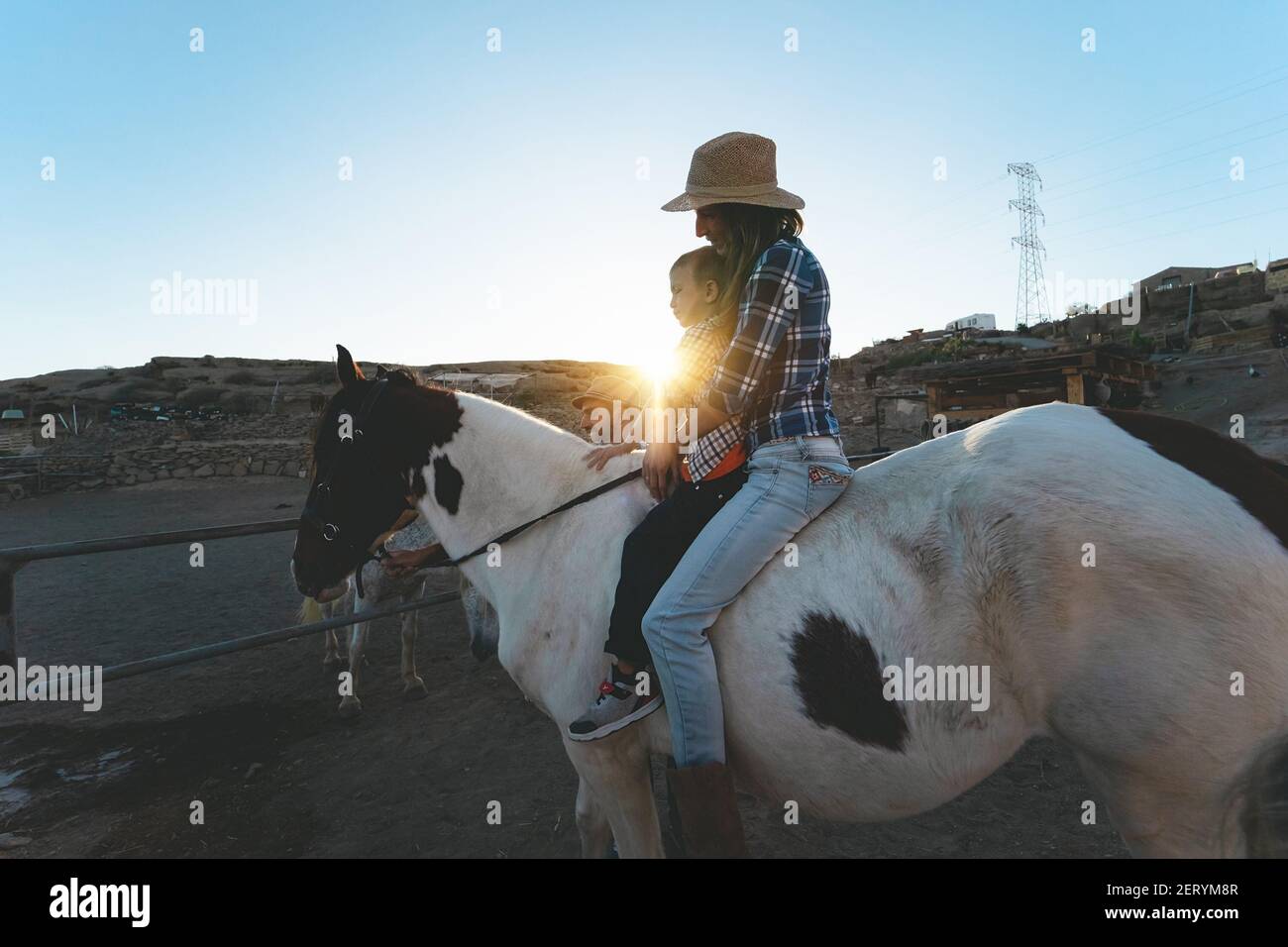Happy family mother and daughter having fun riding horse inside ranch ...