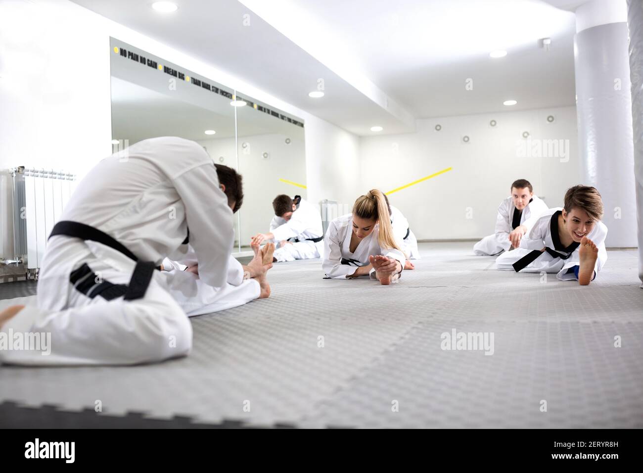 Athletes and a para-athlete doing leg splits together, martial art ...