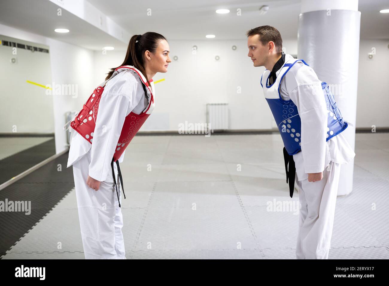 Young man and a young woman bowing before taekwondo combat practice ...