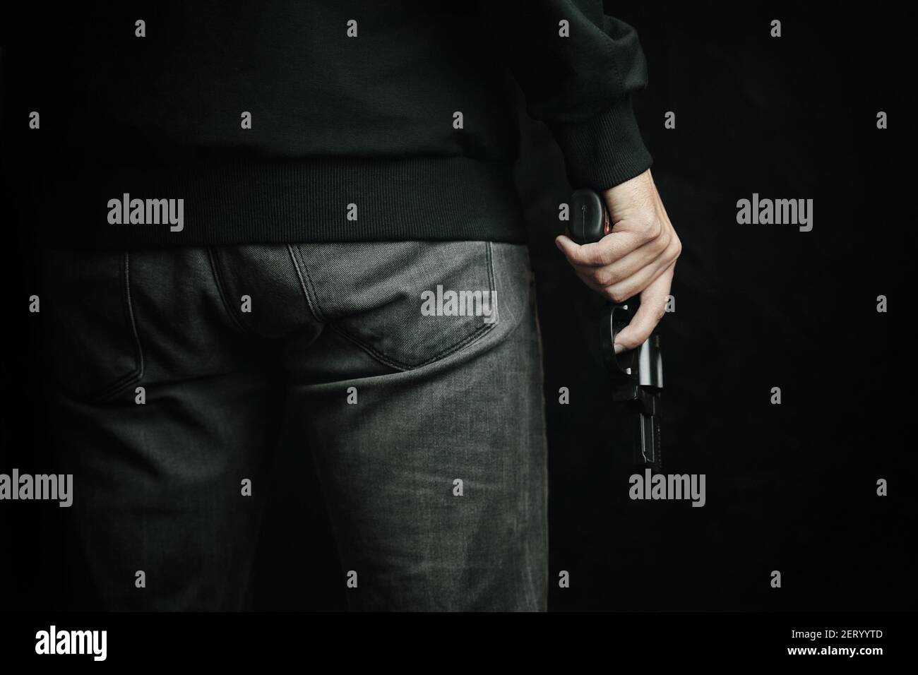 Criminal with revolver in his hand. Man in dark clothing is holding gun ...