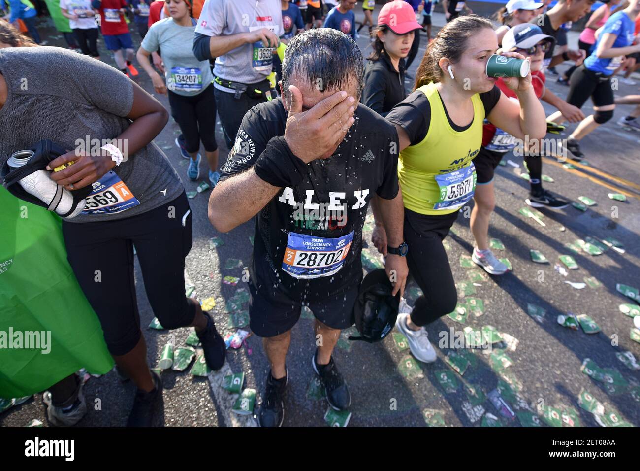A marathon runner wipes his farce after being doused with a cup of ...