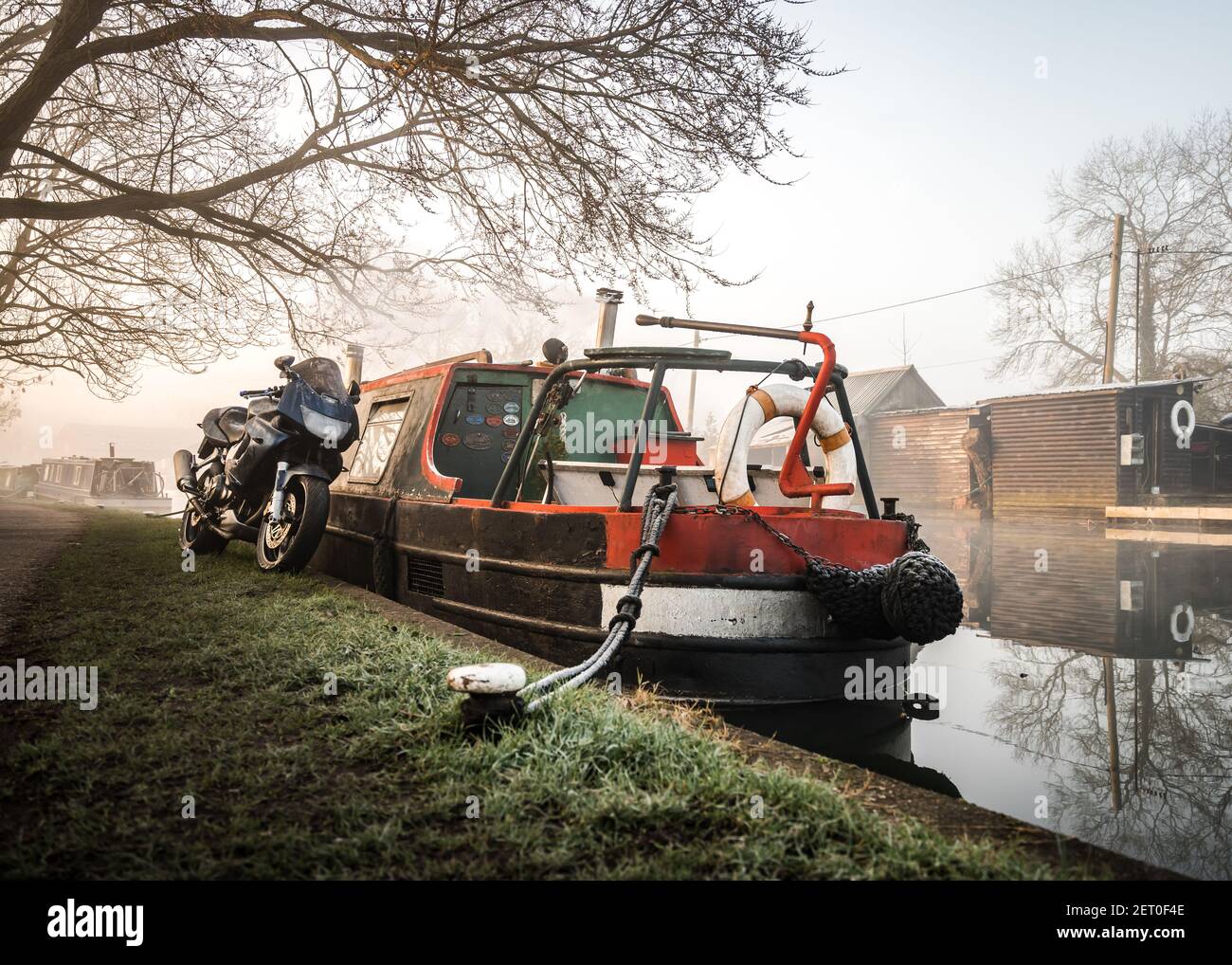 Motorbike parked next to narrow canal house boat side of river as sun ...