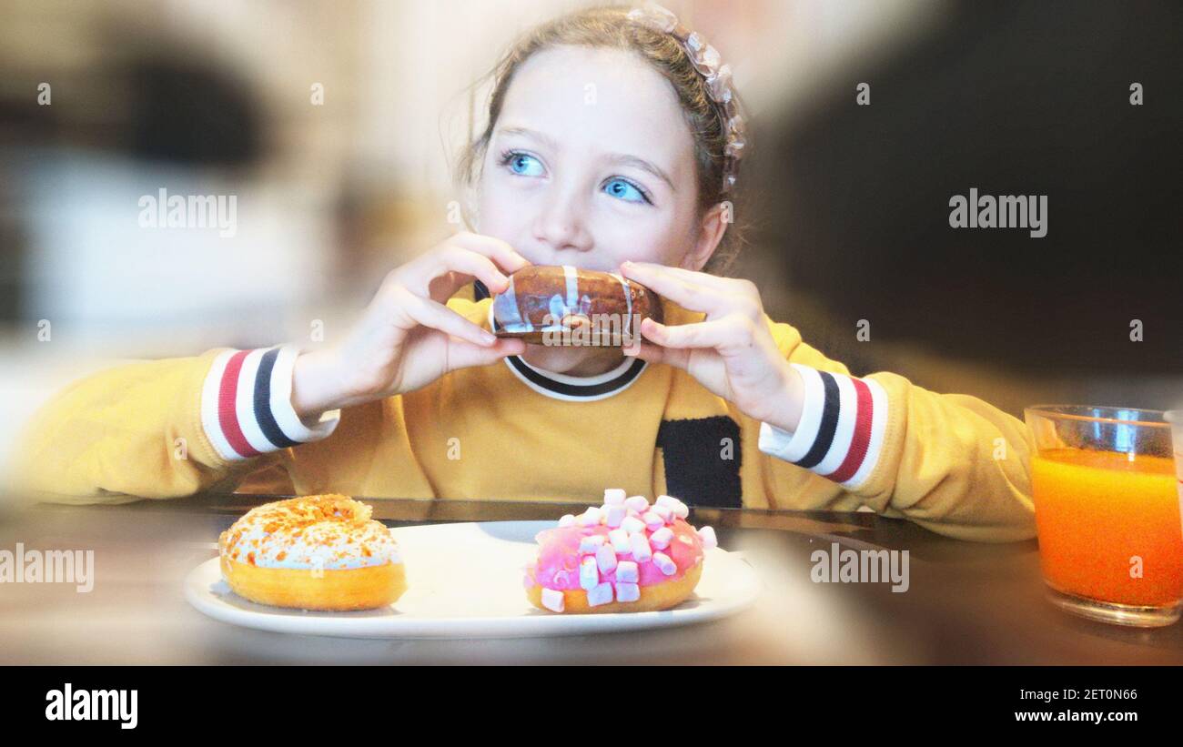 Portrait of a smiling girl eating a doughnut Stock Photo - Alamy