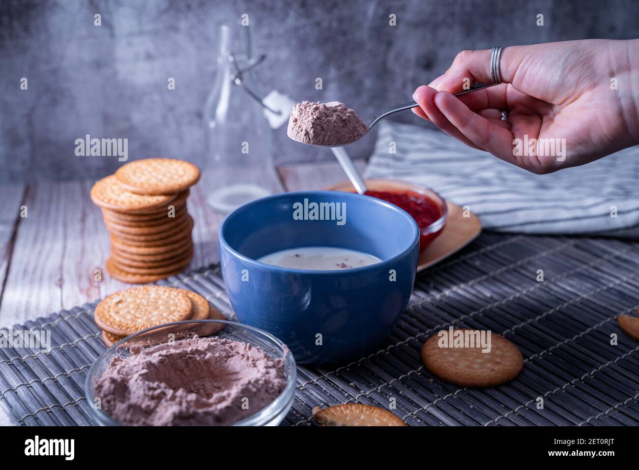A hand making cocoa milk with powdered cocoa in a cup next to Maria ...