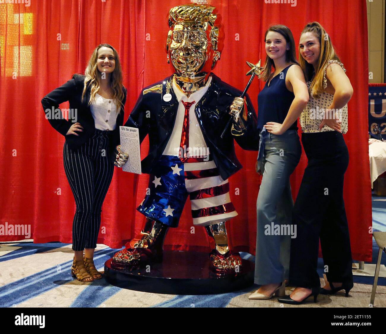 Attendees are photographed with the "Golden Trump" statue in the ...