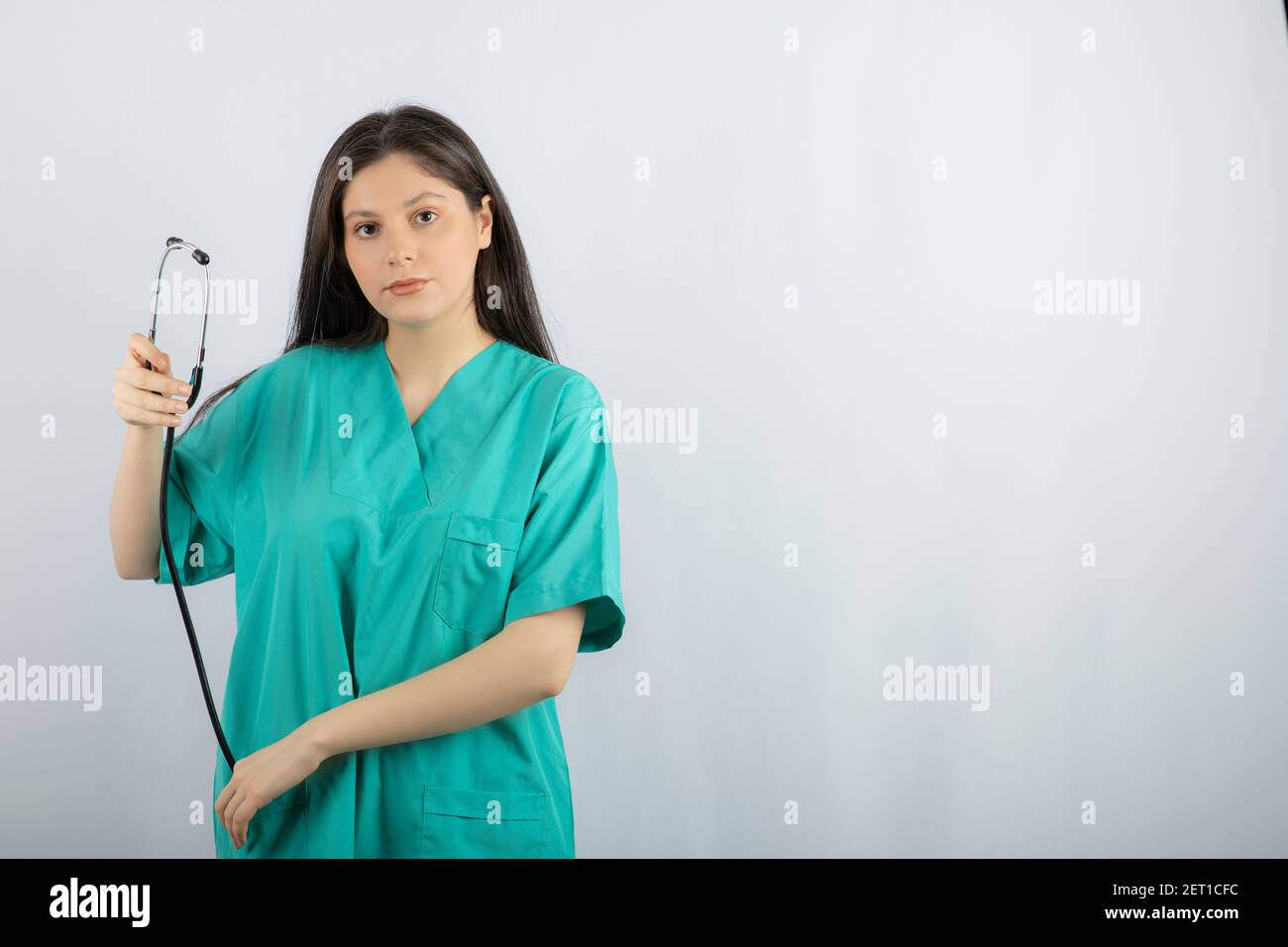 Portrait of female nurse holding stethoscope on white background. High ...