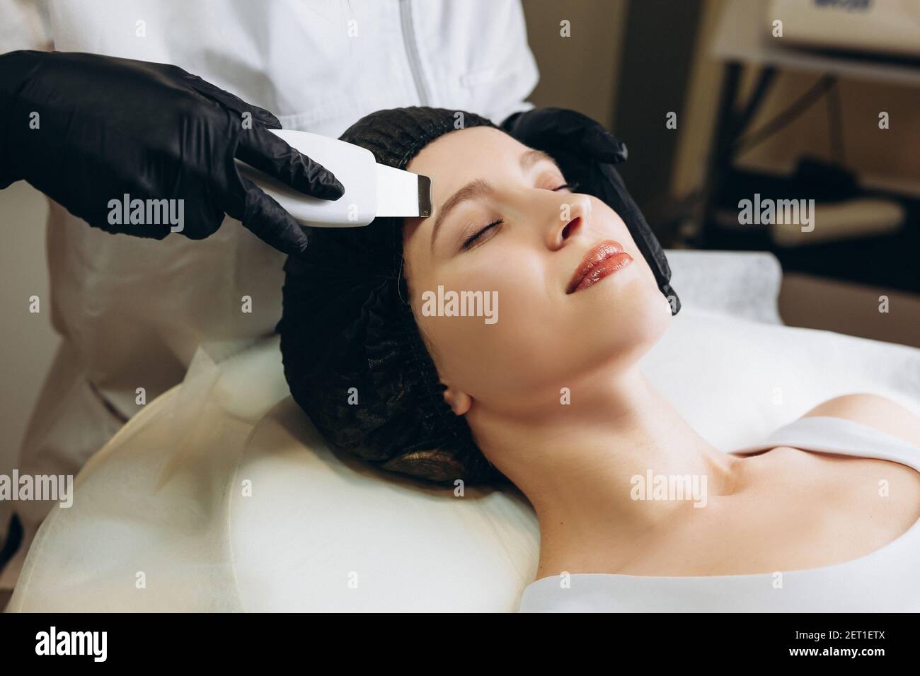 Young woman having machine cosmetology procedure for face rejuvenation ...