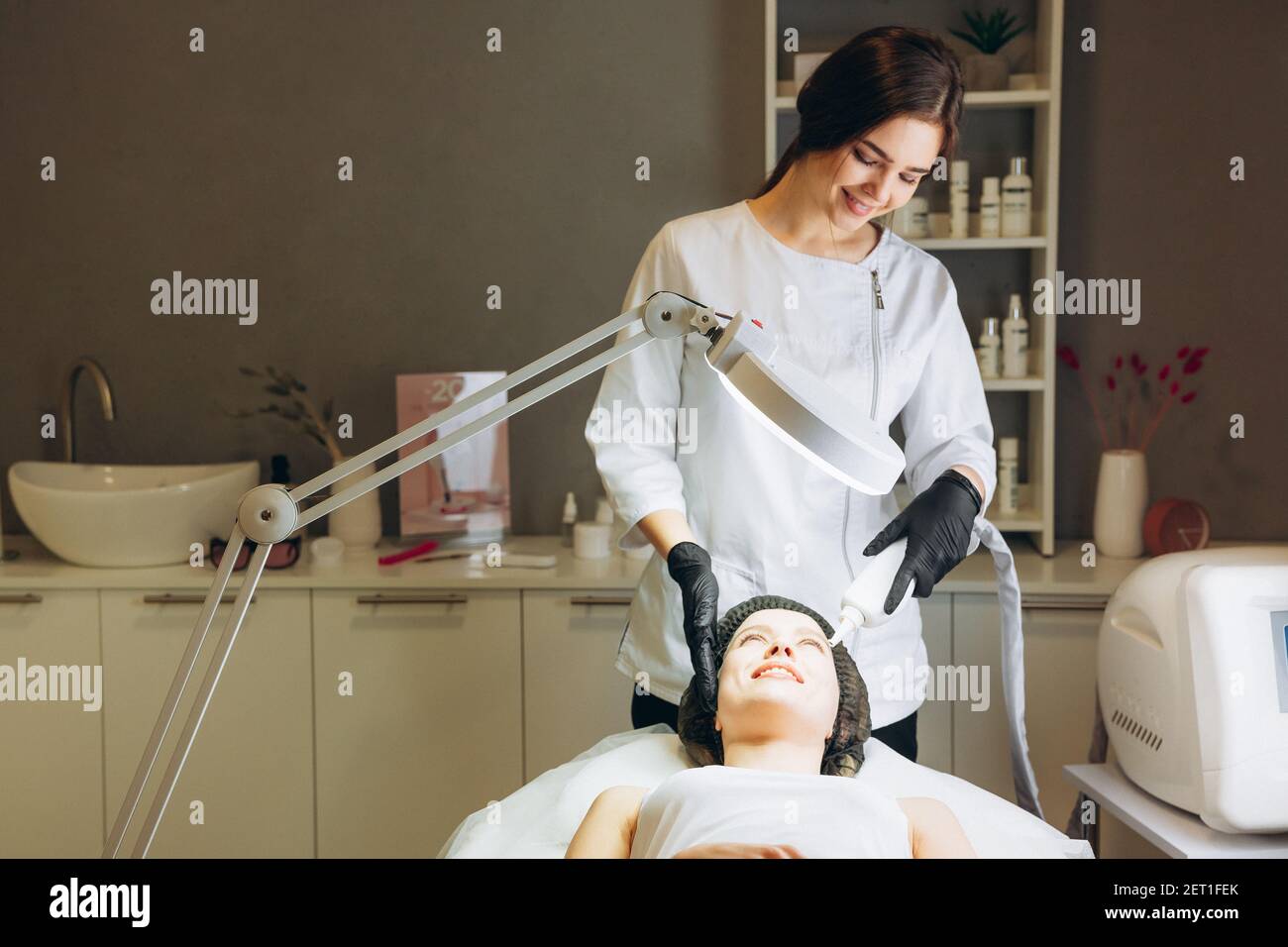 Young woman having machine cosmetology procedure for face rejuvenation ...