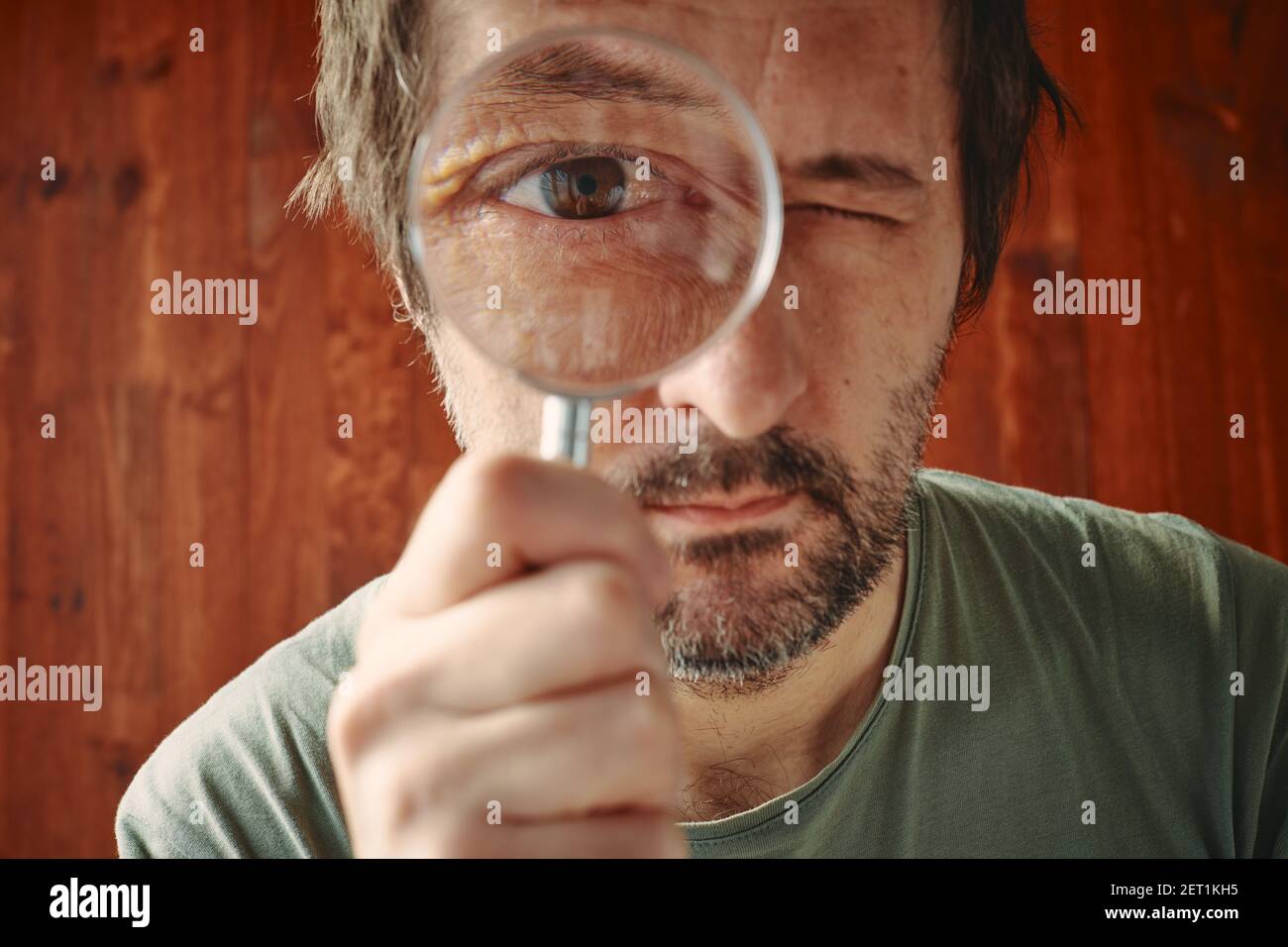Curious man looking through magnifying glass with intense desire to ...
