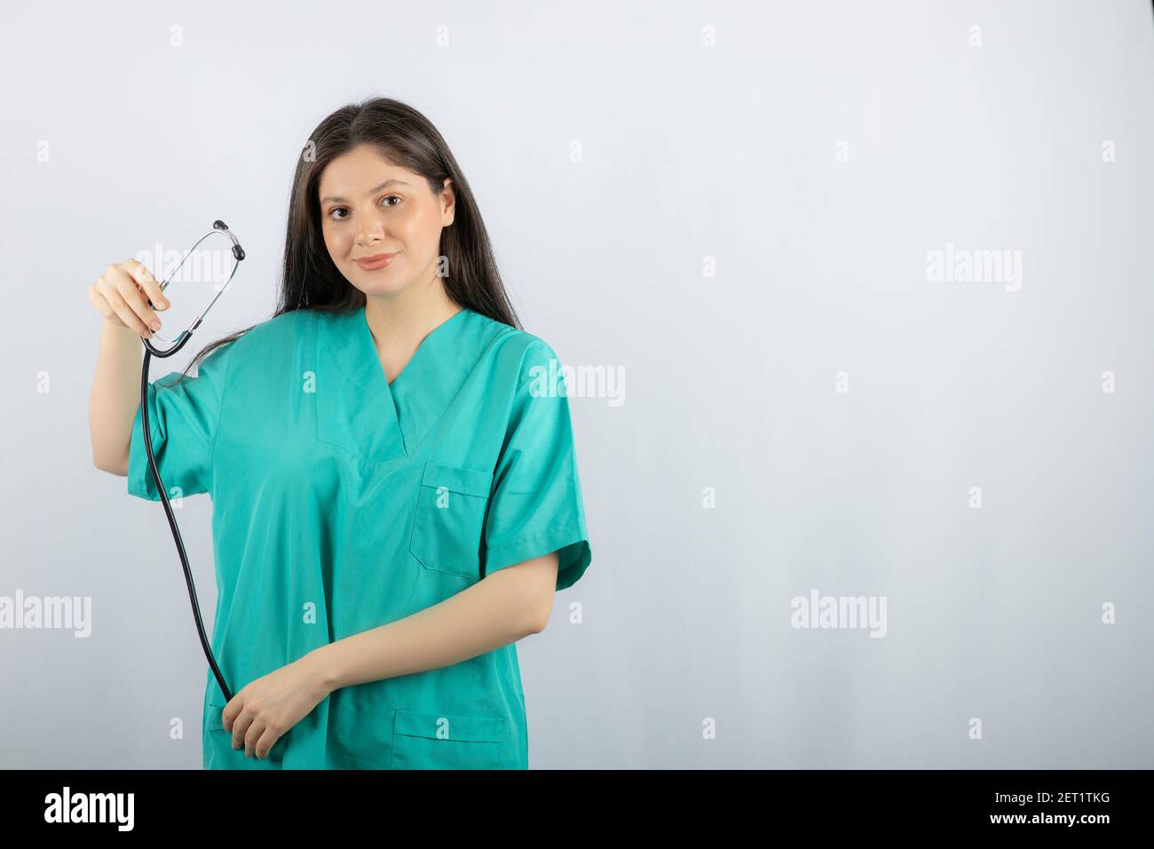 Portrait of female nurse holding stethoscope on white background. High ...