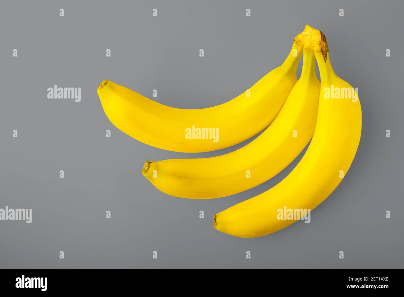 Three yellow bananas on a gray background. The color trend of 2021 is ...