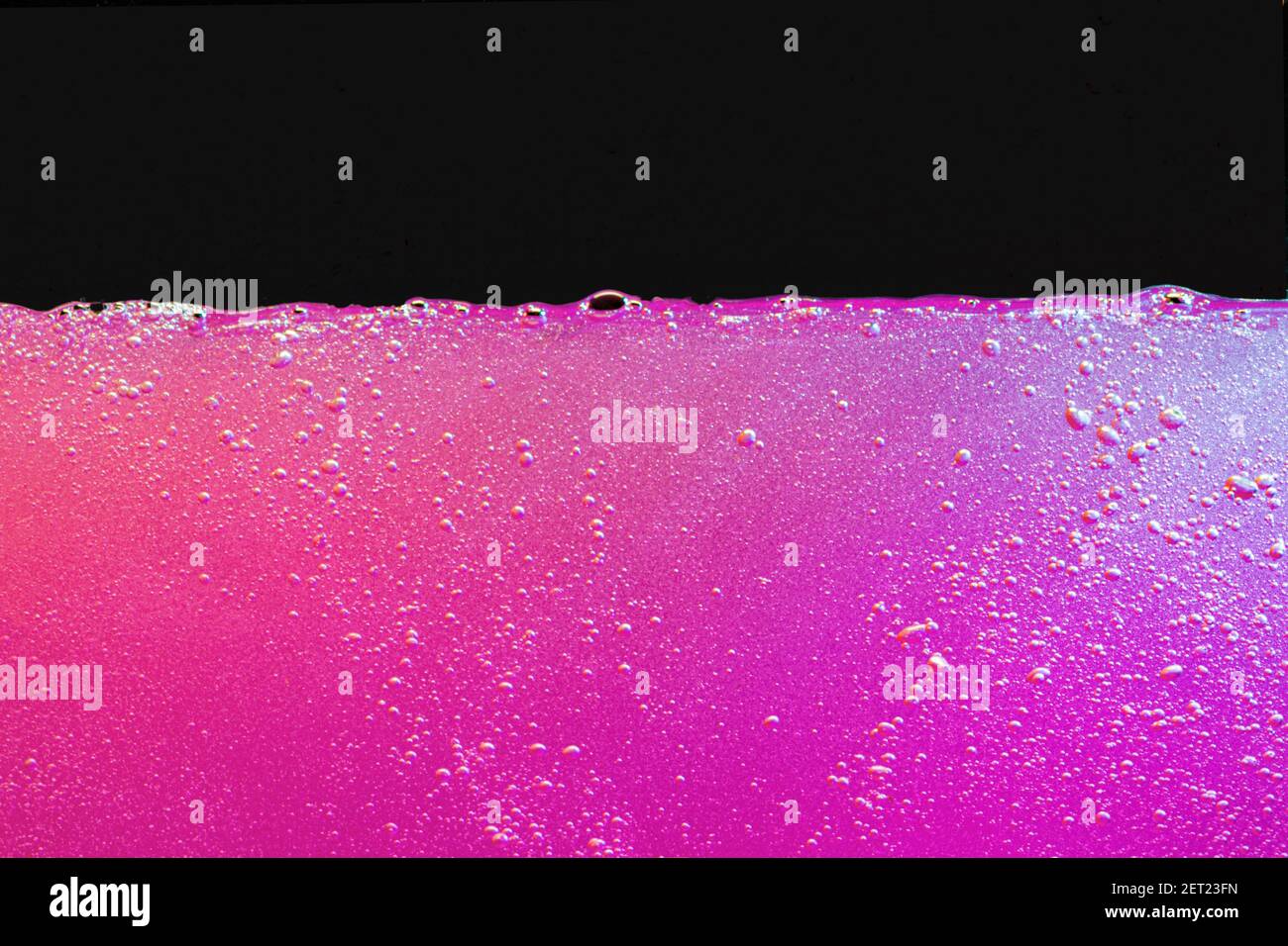 Pink bubbly boiling water against black background Stock Photo - Alamy