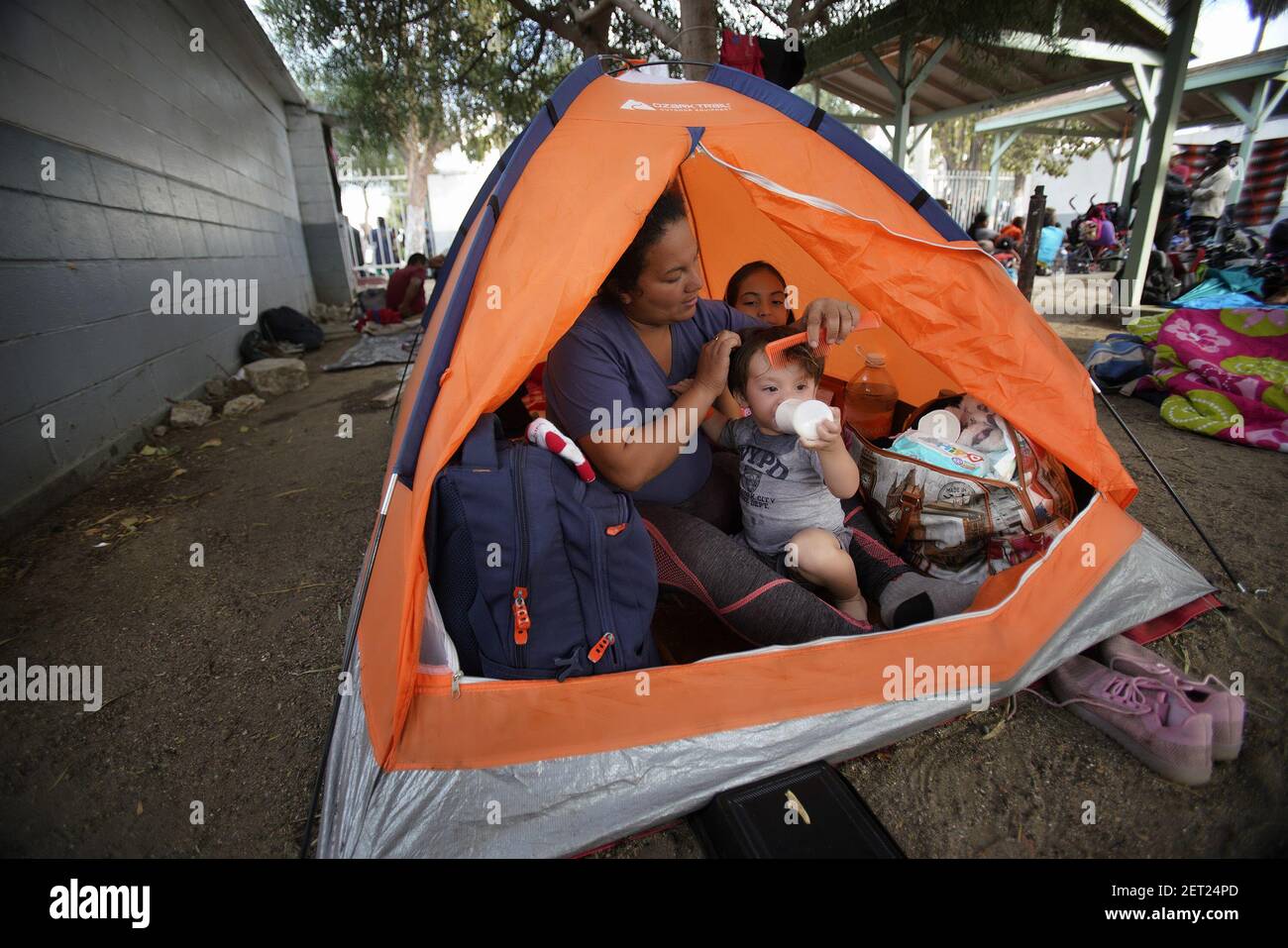 Sitting her their tent Ana Marlene Bueso combs the hair of her son ...