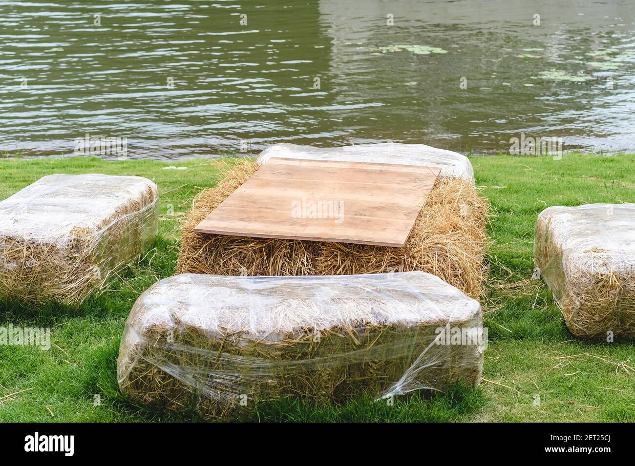 Seats and tables made from straw bales for event and party laid on lawn ...