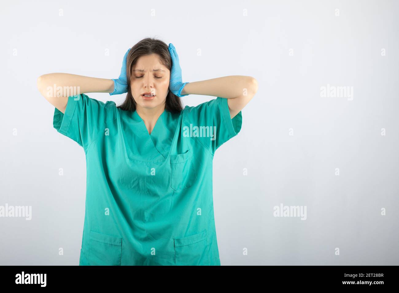 Female doctor wearing green medical uniform and holding head. High ...
