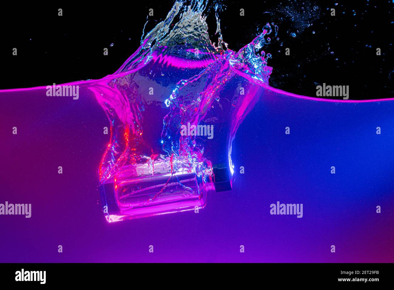 Perfume bottle diving into the water with a splash in neon light Stock ...