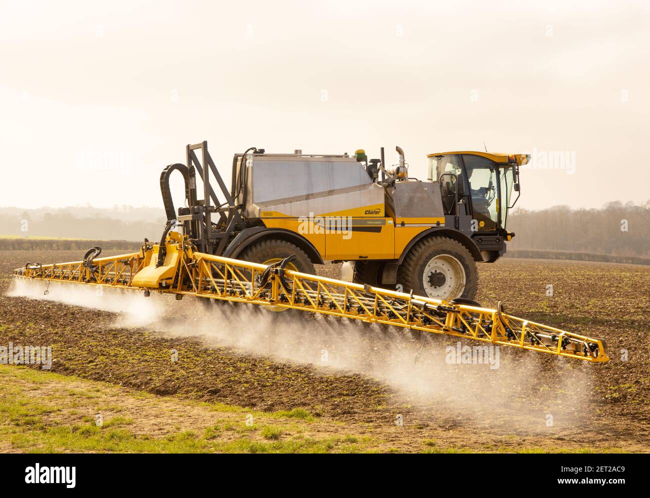 Farmer using a self-propelled crop sprayer in a field in early spring ...